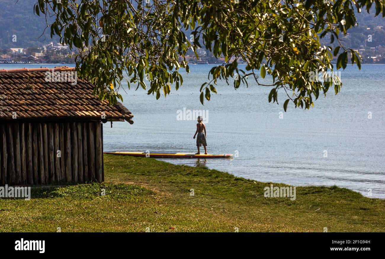 A boy standing on a stand-up paddle in the lake Stock Photo - Alamy