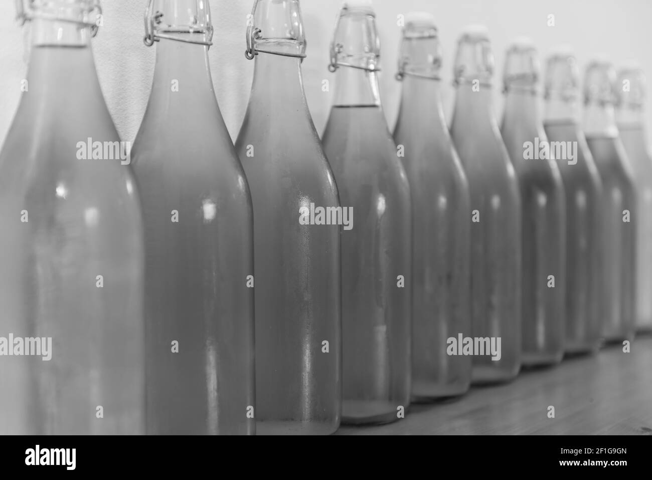 Black and white photo of a row of flip top bottles of home made cider ...