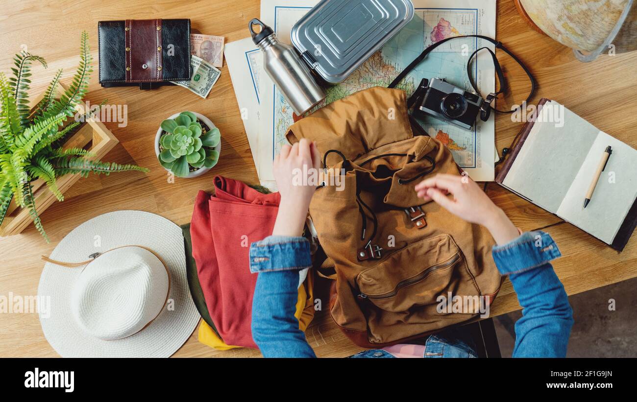 Top view of young woman packing for vacation trip holiday, desktop ...