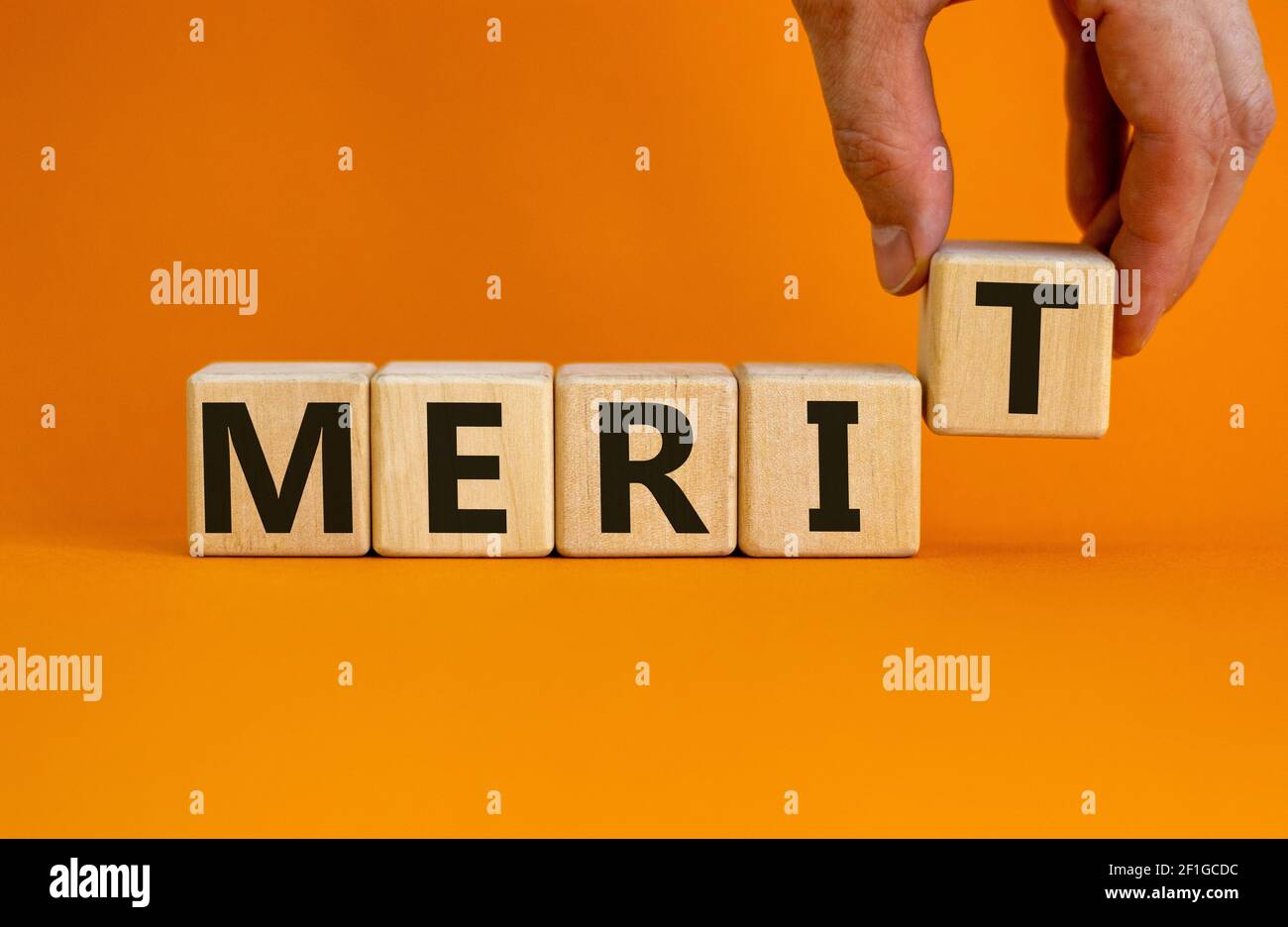 Merit symbol. Wooden cubes with the word 'merit'. Businessman hand ...