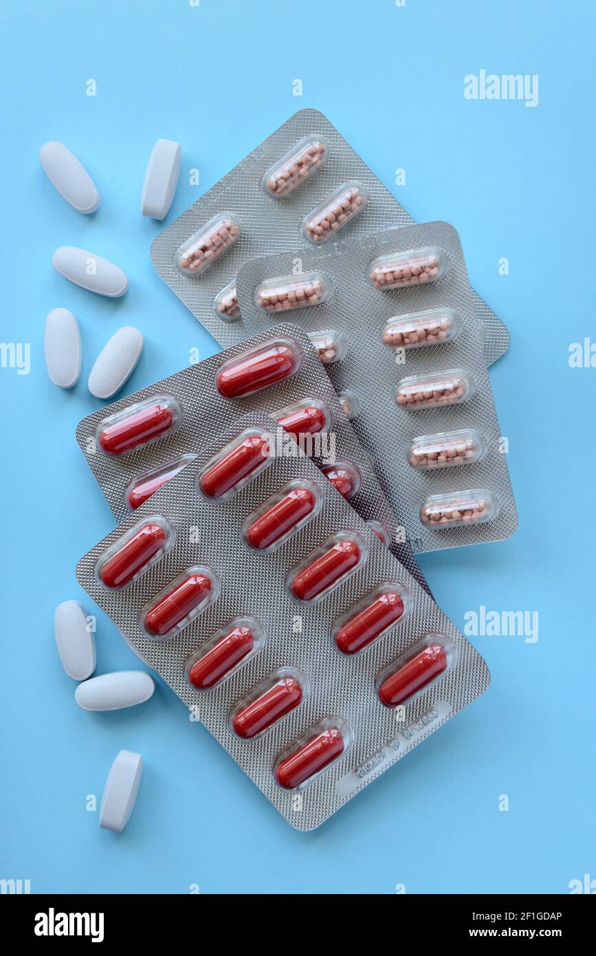 Assorted pharmaceutical medicine pills, tablets and capsules over blue ...