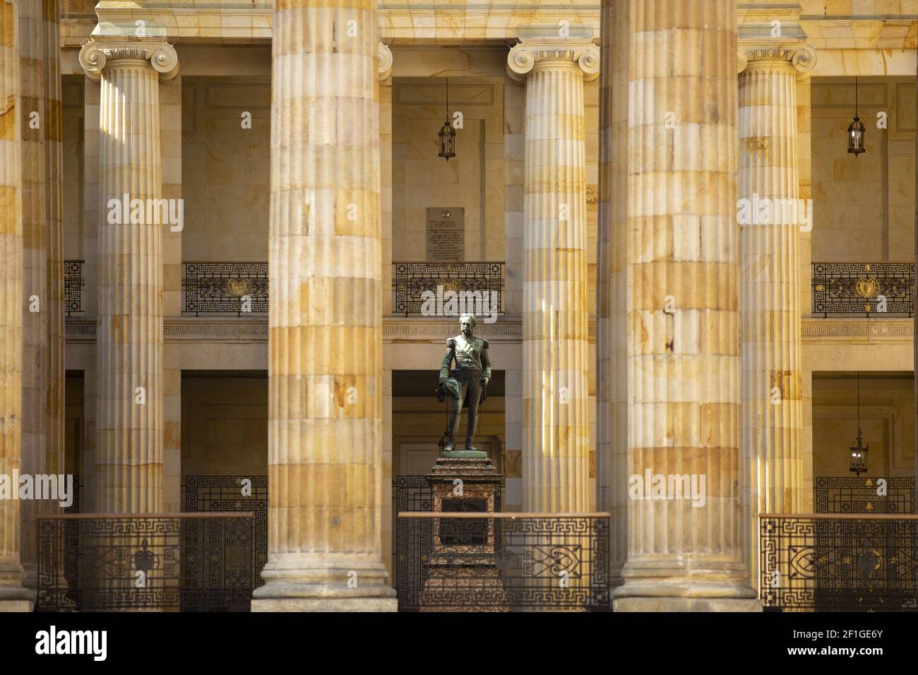 The front view of a senate building with a man's statue in front of it ...