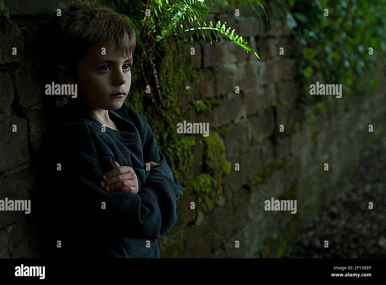 Young Boy with Folded Arms Leaning Against Wall Stock Photo - Alamy