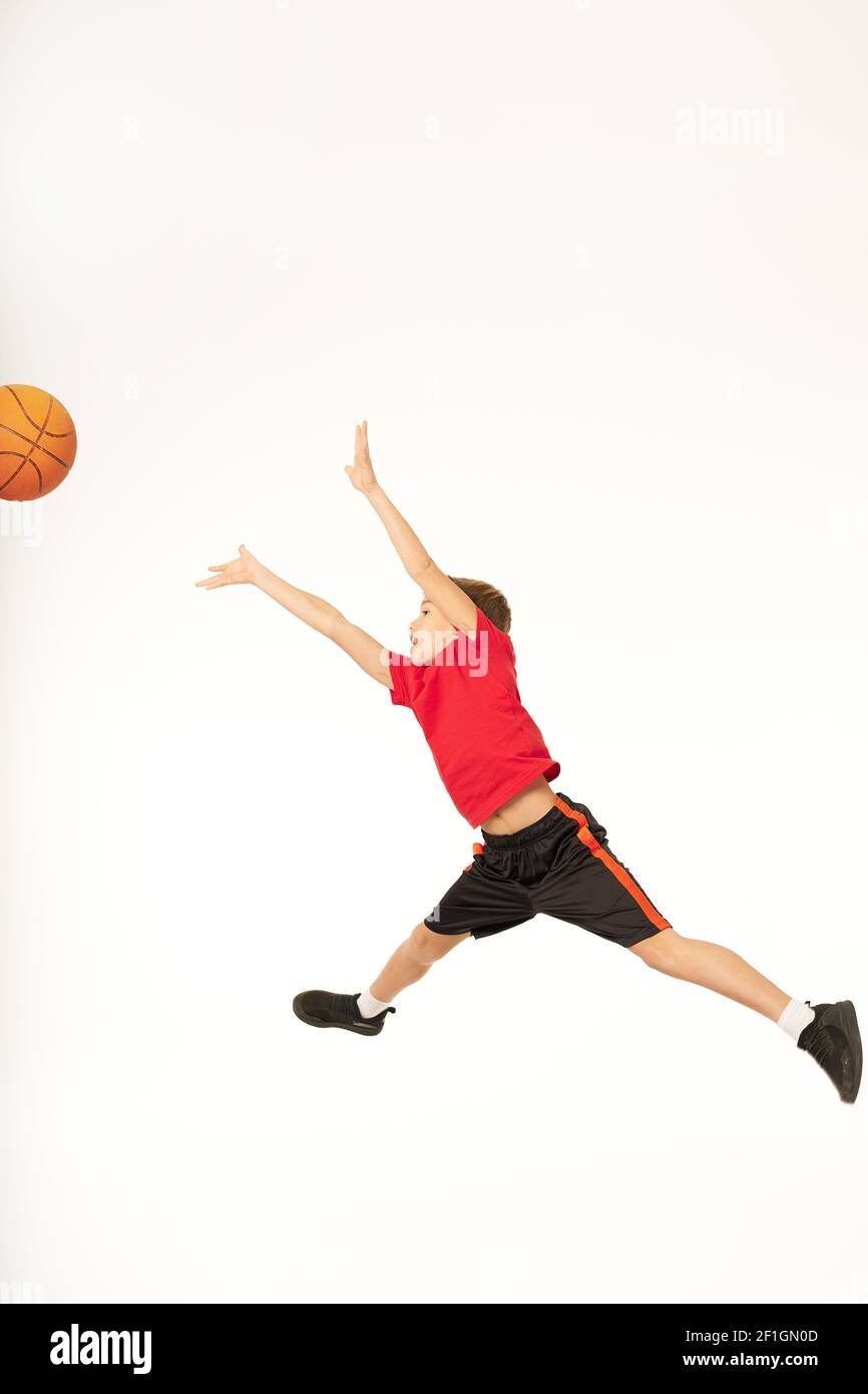 Cute male child basketball player making jump and reaching out hands to ...