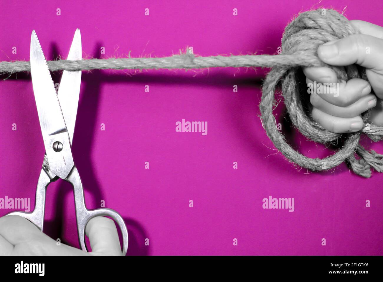 Hand wit scissors cutting rope symbolizing the lack of freedom of women ...