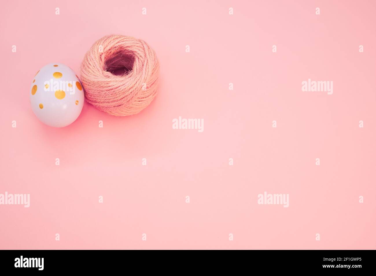 A decorated egg on white plate and a thread isolated on pink background ...