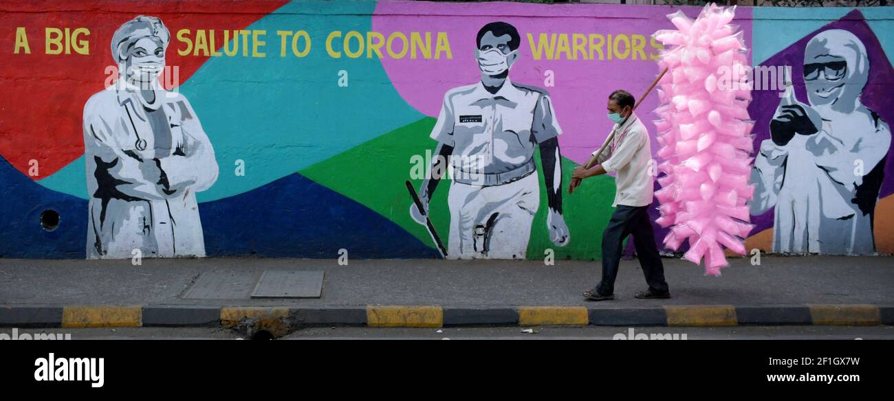 A cotton candy seller wearing a face mask walks past a graffiti painted ...