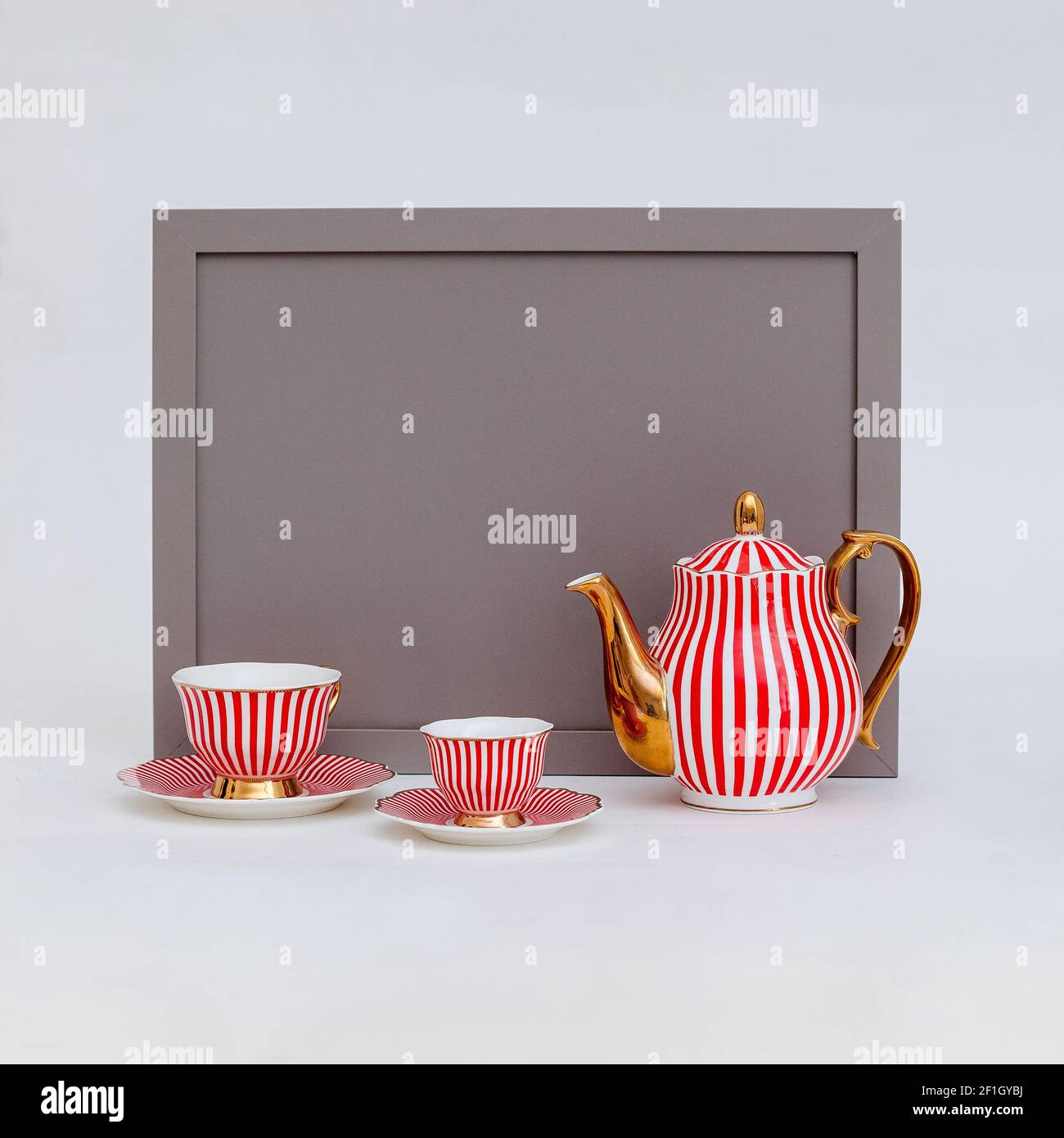 A striped teacup, a coffee cup, a teapot and a tray isolated on a white ...