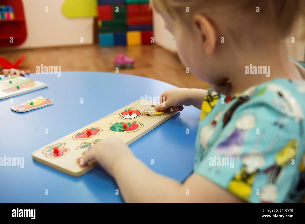 Toddler girl lays puzzles in the kindergarten. View from above Stock ...