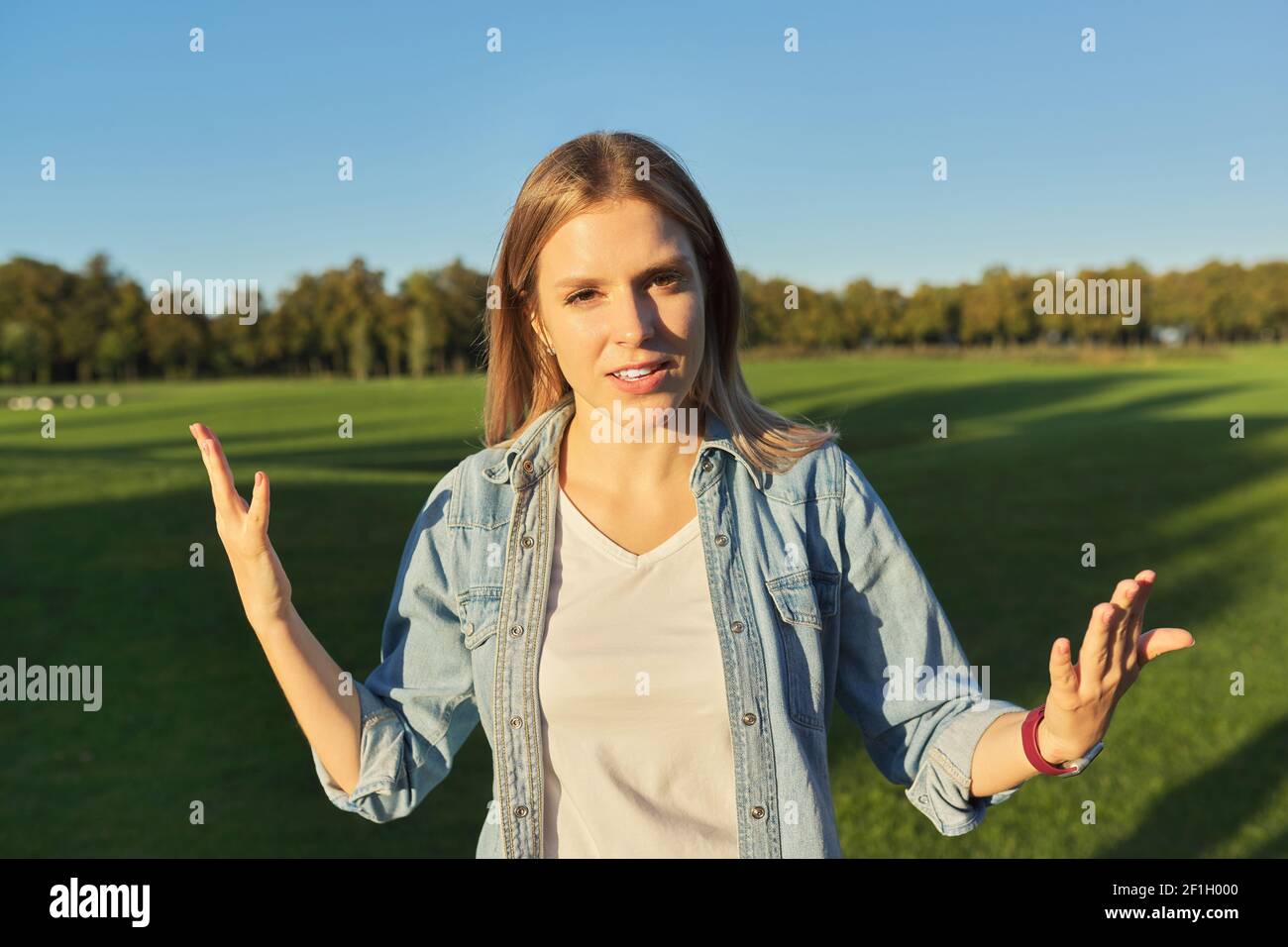 Gesturing young beautiful woman talking at camera Stock Photo - Alamy