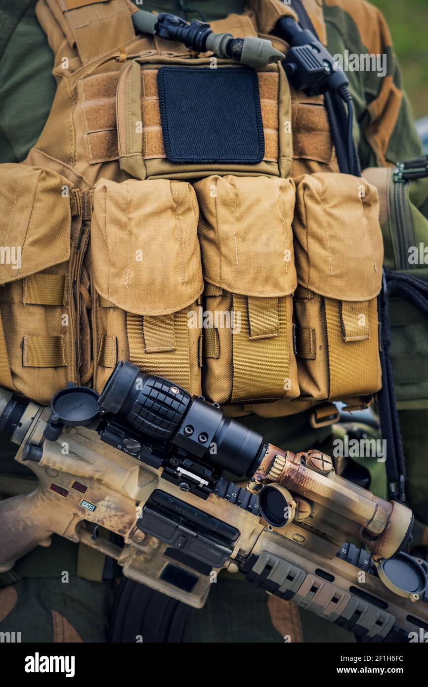 A soldier with an assault rifle wearing a tactical load-carrying vest ...