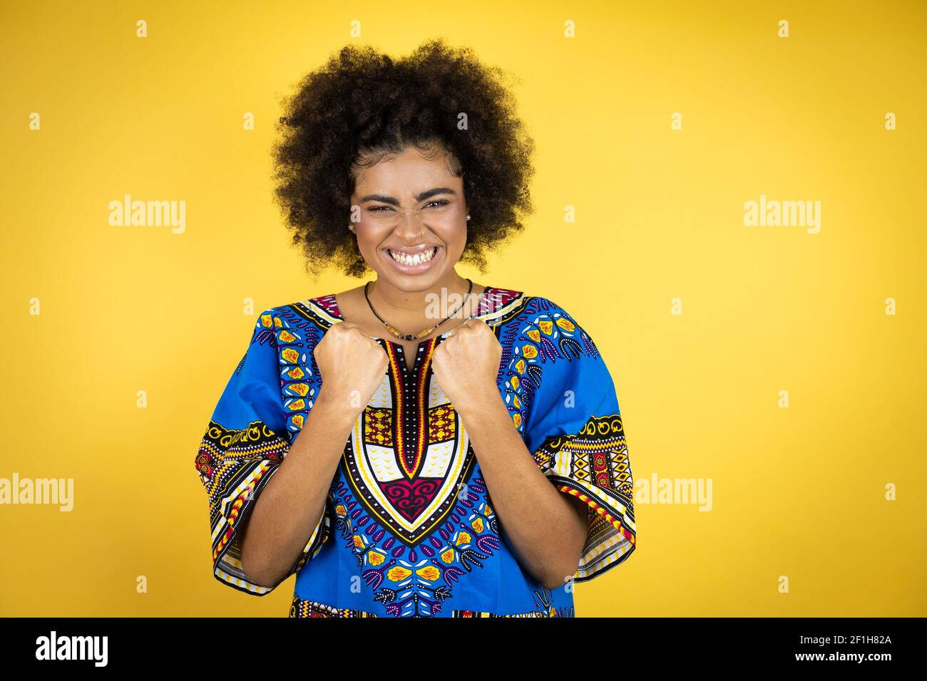 African american woman wearing african clothing over yellow background ...