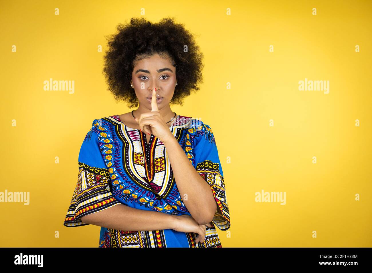 African american woman wearing african clothing over yellow background ...