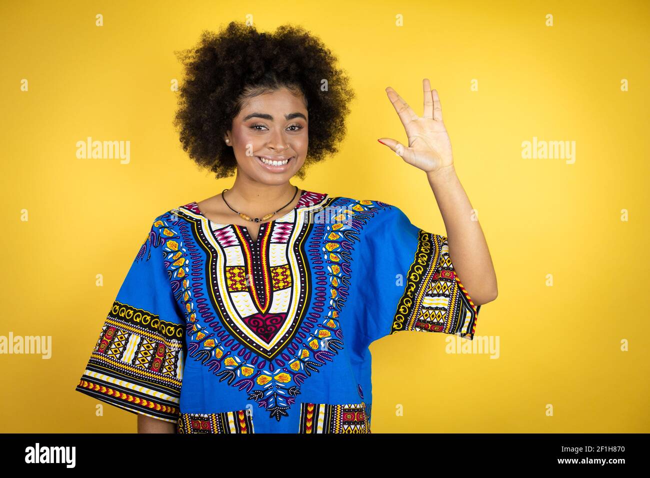 African american woman wearing african clothing over yellow background ...