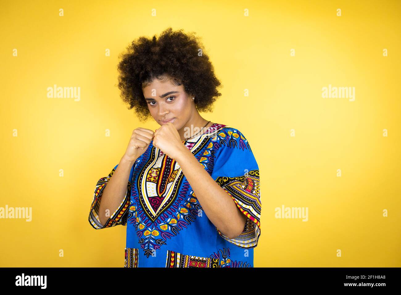African american woman wearing african clothing over yellow background ...