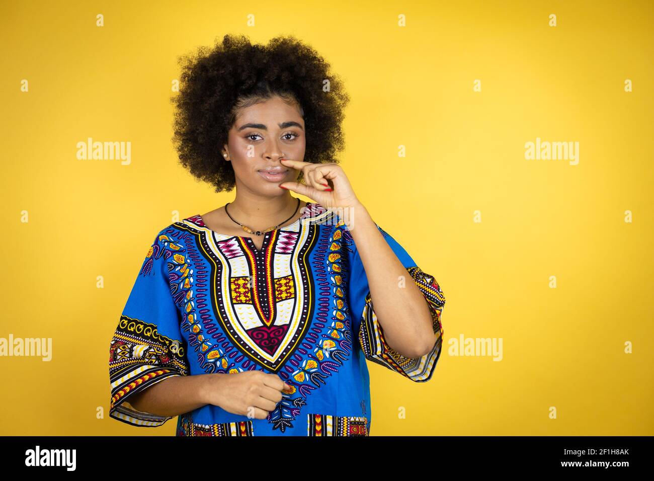 African american woman wearing african clothing over yellow background ...