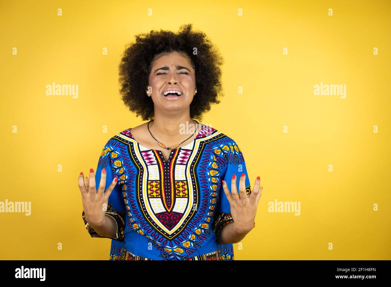 African american woman wearing african clothing over yellow background ...