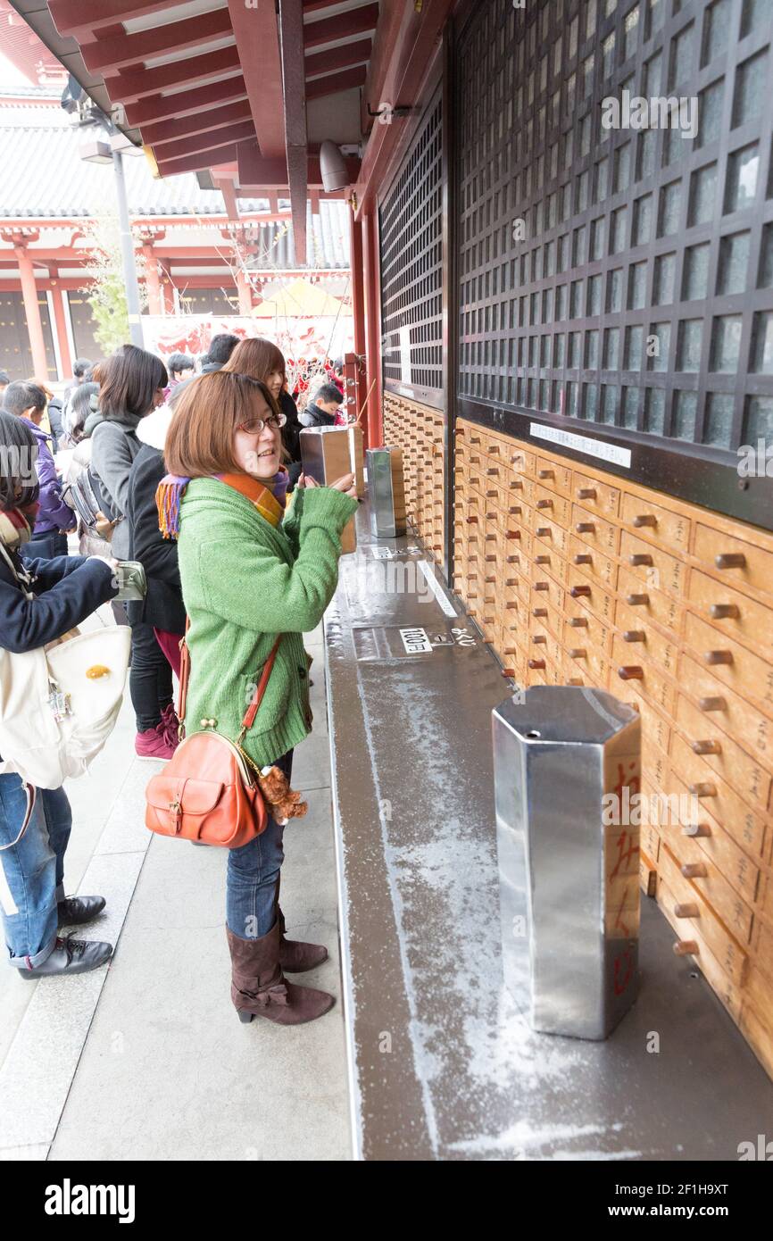 Woman drawing an Omikuji stick as part of Omikuji fortune telling at Sensoji Temple bring New ...