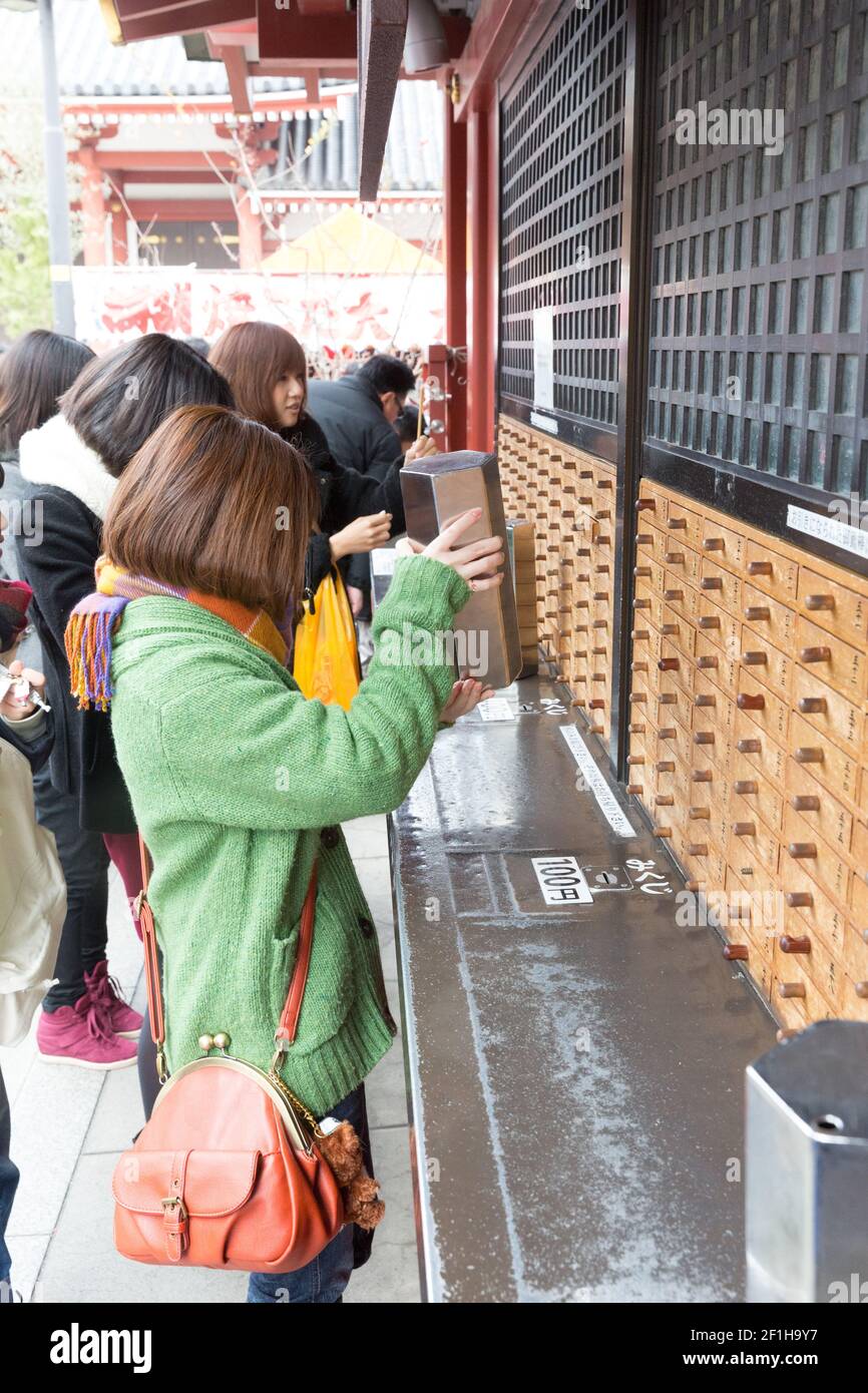 Woman drawing an Omikuji stick as part of Omikuji fortune telling at Sensoji Temple bring New ...