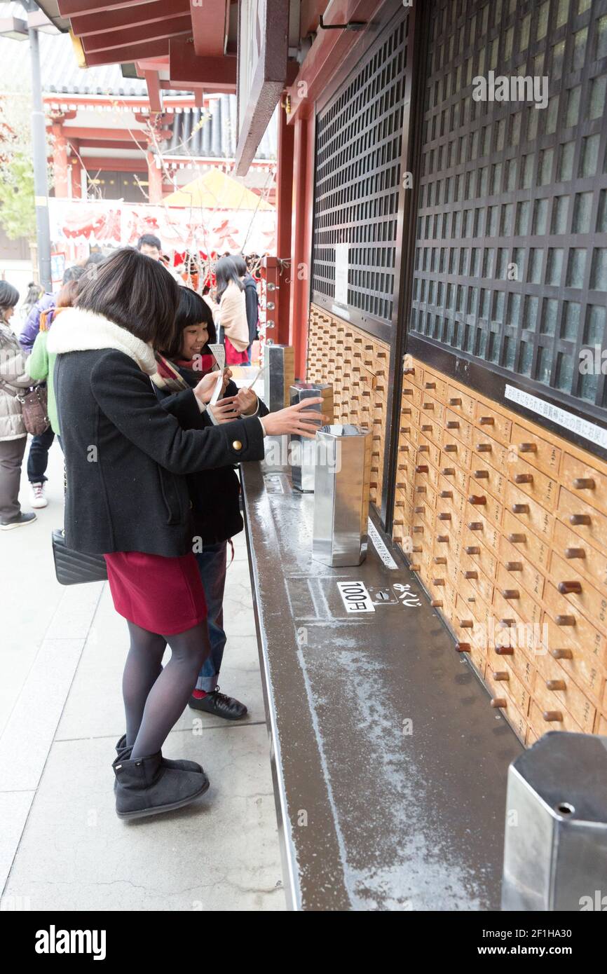 Young Women drawing an Omikuji stick as part of Omikuji fortune telling at Sensoji Temple bring ...