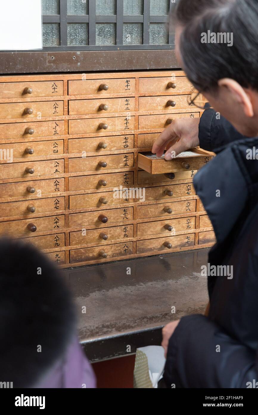 Man collecting his paper strip fortune as a as part of Omikuji fortune ...