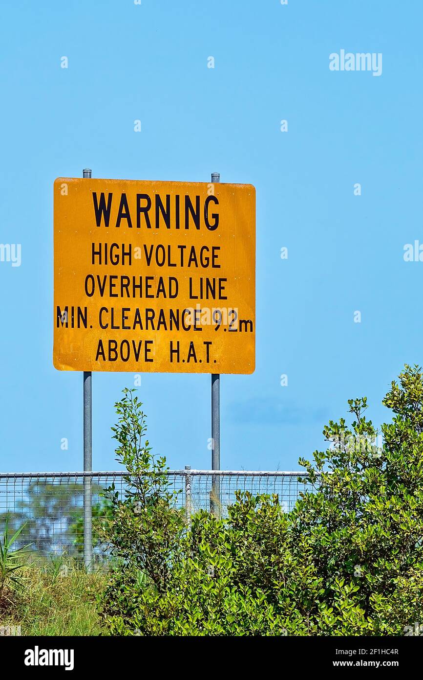 High voltage overhead line warning sign against a blue sky Stock Photo ...