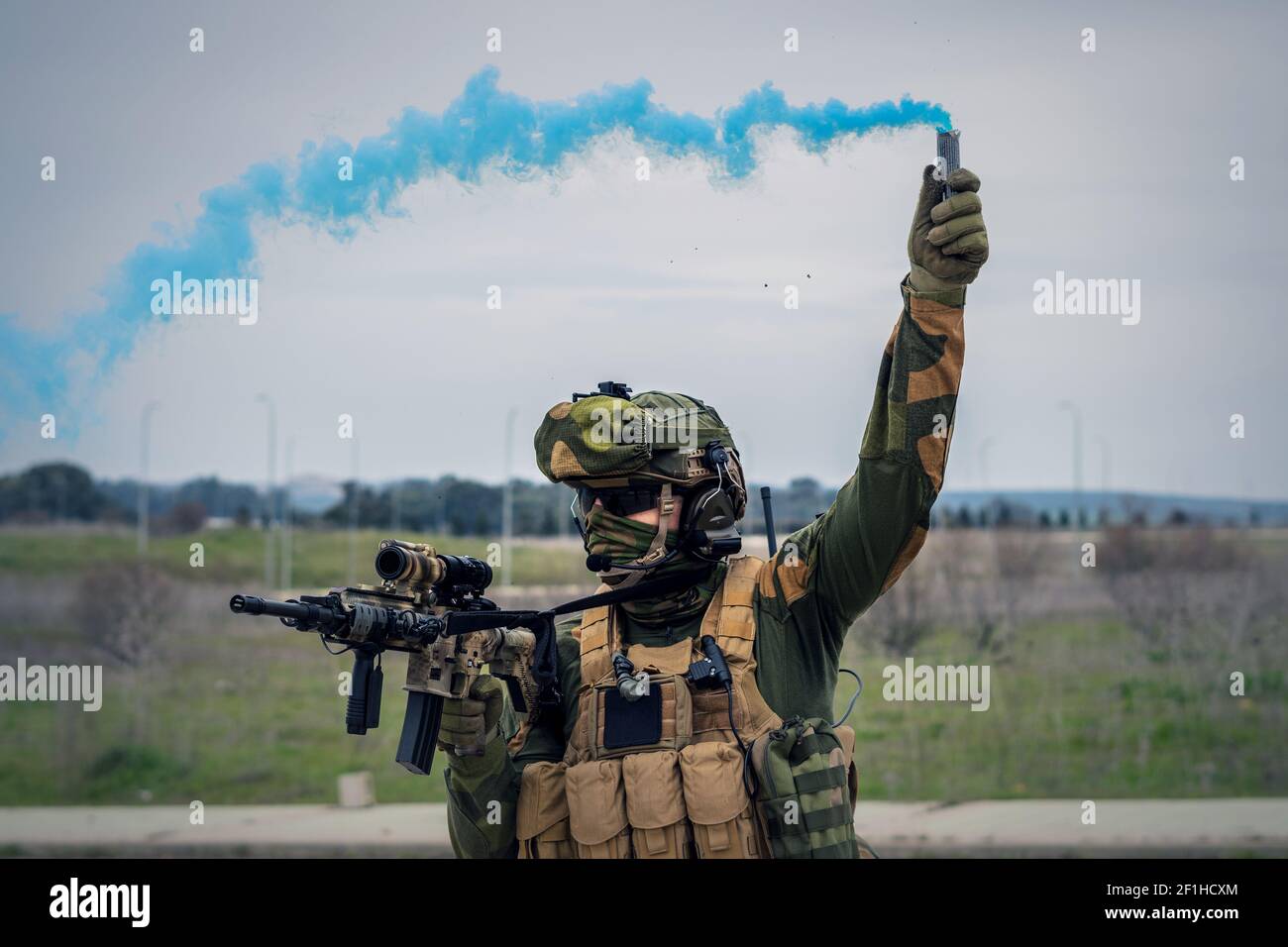 A special forces soldier holding an assault rifle and a blue smoke bomb ...
