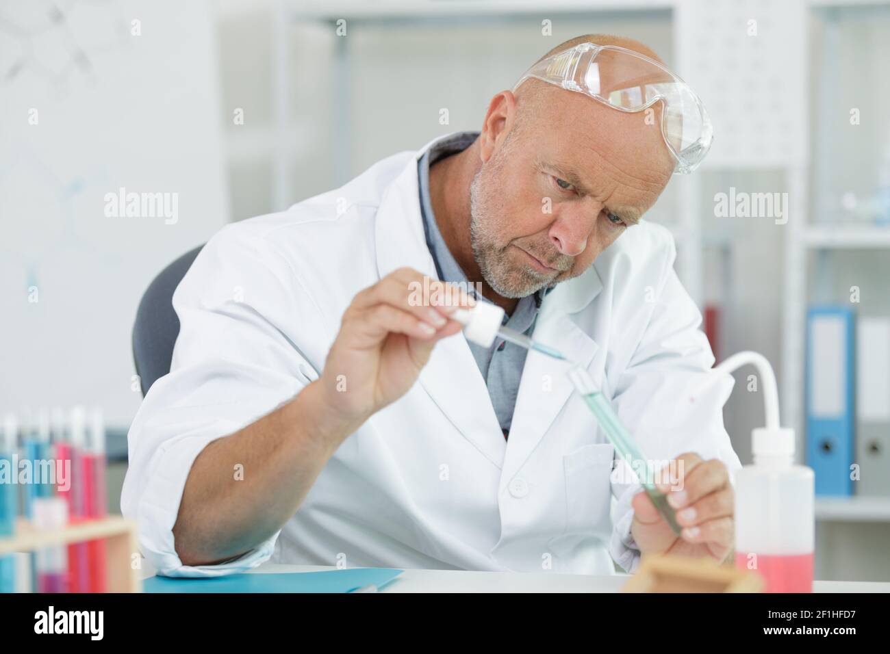 mature scientist dripping reagent into test tube Stock Photo - Alamy