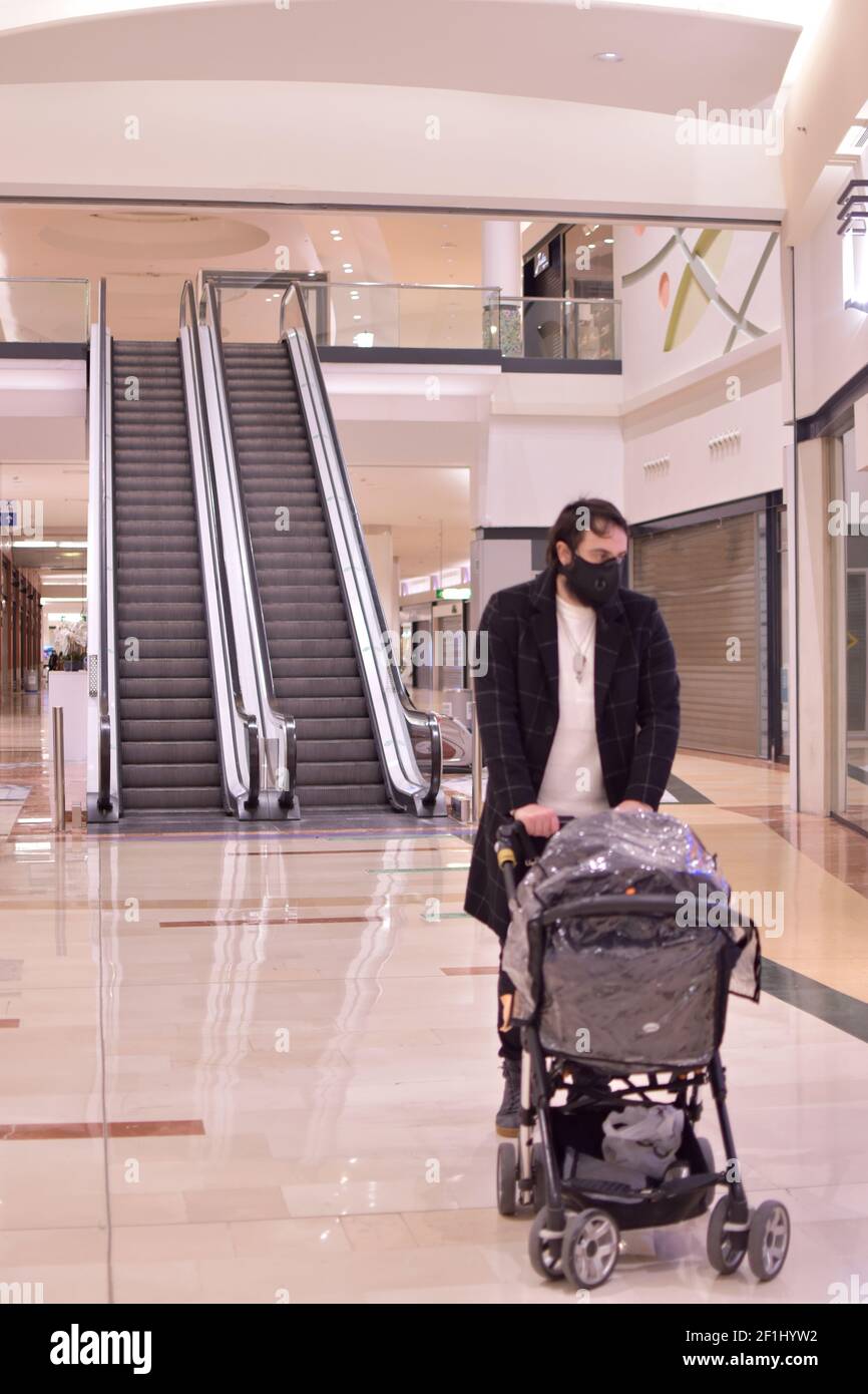 Man walking in empty mall. Single dad taking a walk with a stroller ...