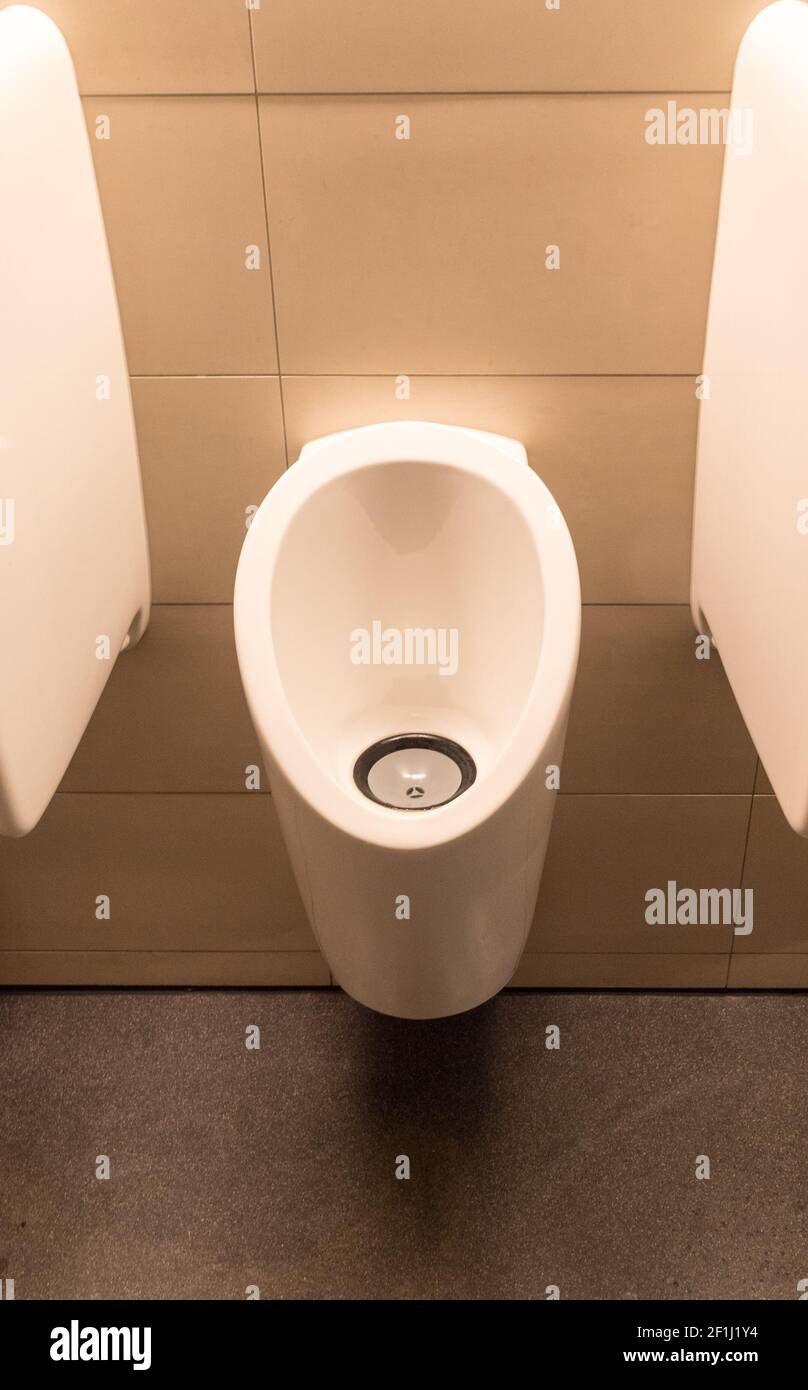 Modern white ceramic urinal in a brown room Stock Photo - Alamy