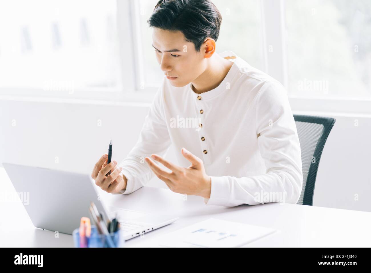 The Asian team leader is working remotely with the staff via video call ...