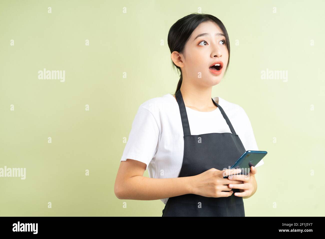 Asian waitress holding the phone with a surprised face Stock Photo - Alamy