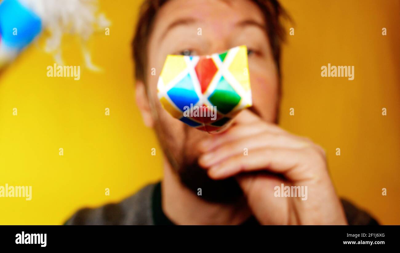 Man celebrates the carnival, with party horn on a yellow background ...