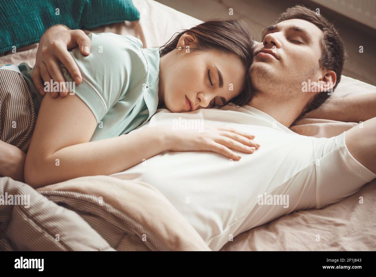 Adorable couple lying in bed and napping together embracing in a ...