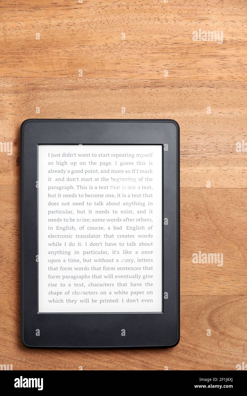 Electronic reader with text on the screen on a wooden surface. Concepts ...