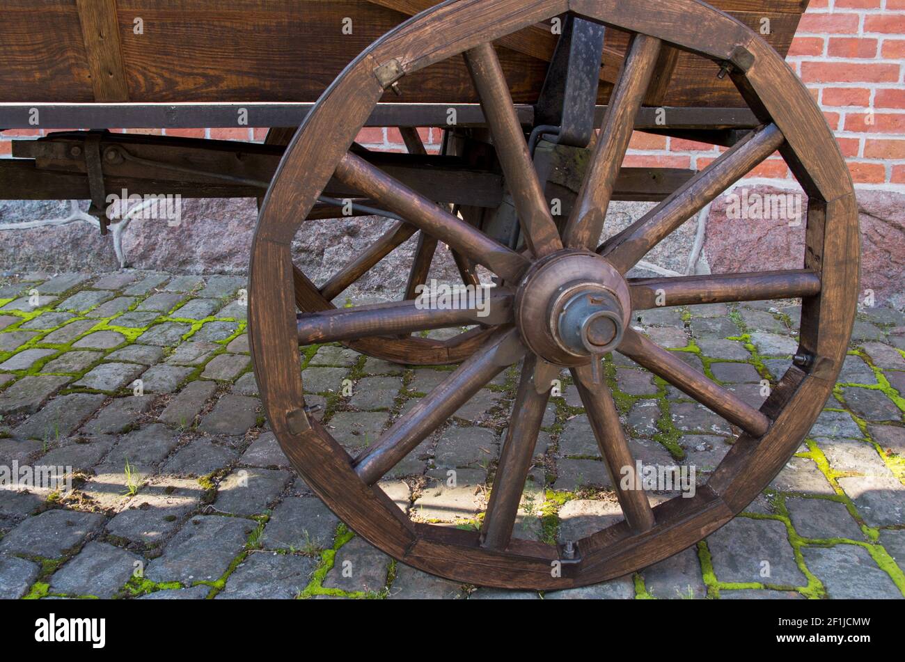 A brown wheel with a wooden rim and spokes at the left rear and the ...