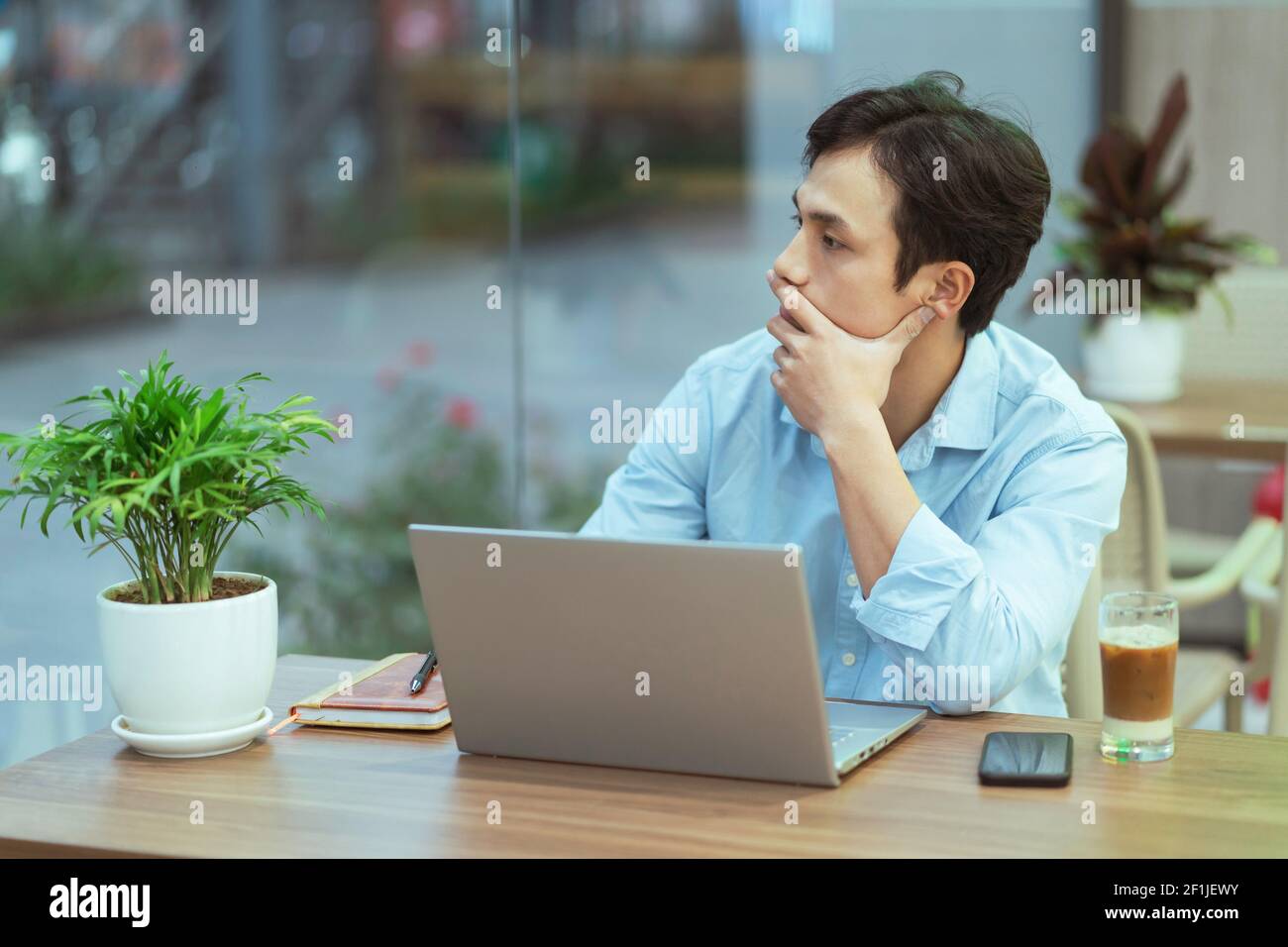Asian man sitting working alone at a coffee shop Stock Photo - Alamy