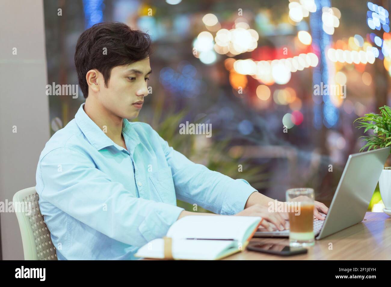 Asian man sitting working alone at a coffee shop Stock Photo - Alamy