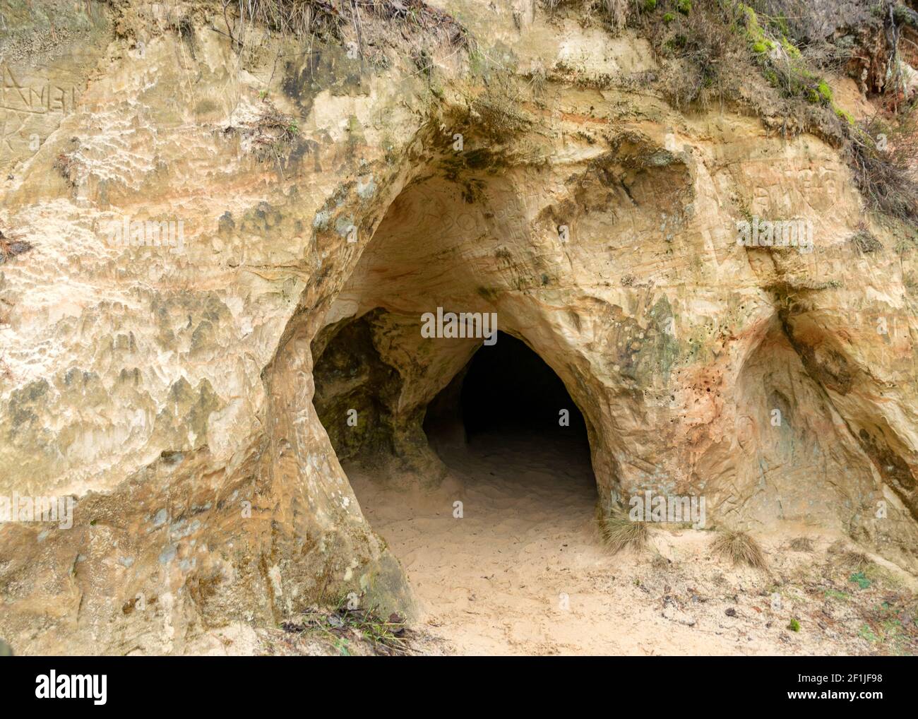 sandstone rock wall and entrance to the cave, the cave is located on ...