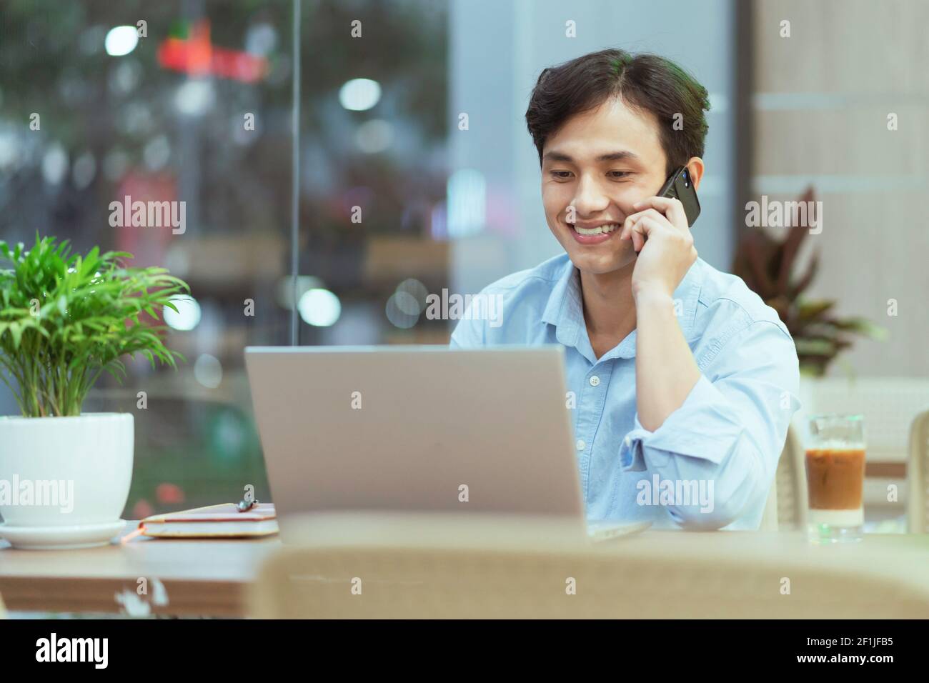 Asian man sitting working alone at a coffee shop Stock Photo - Alamy