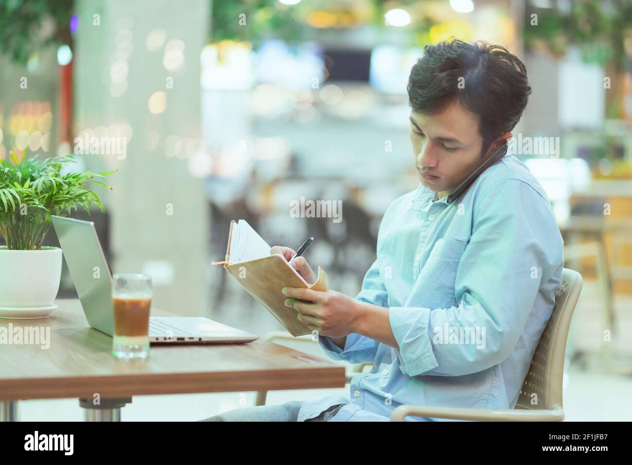 Asian man sitting working alone at a coffee shop Stock Photo - Alamy