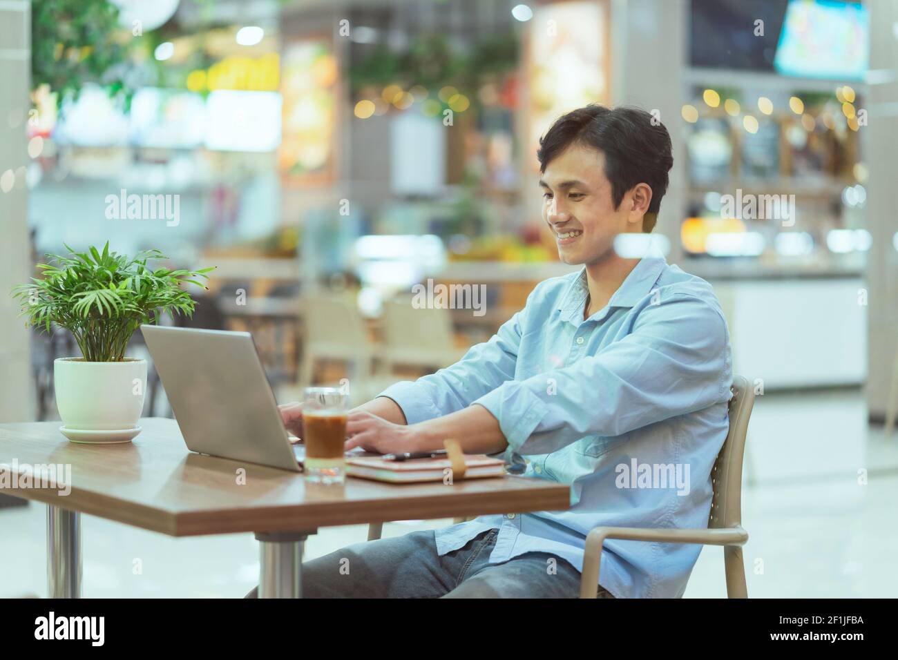 Asian man sitting working alone at a coffee shop Stock Photo - Alamy