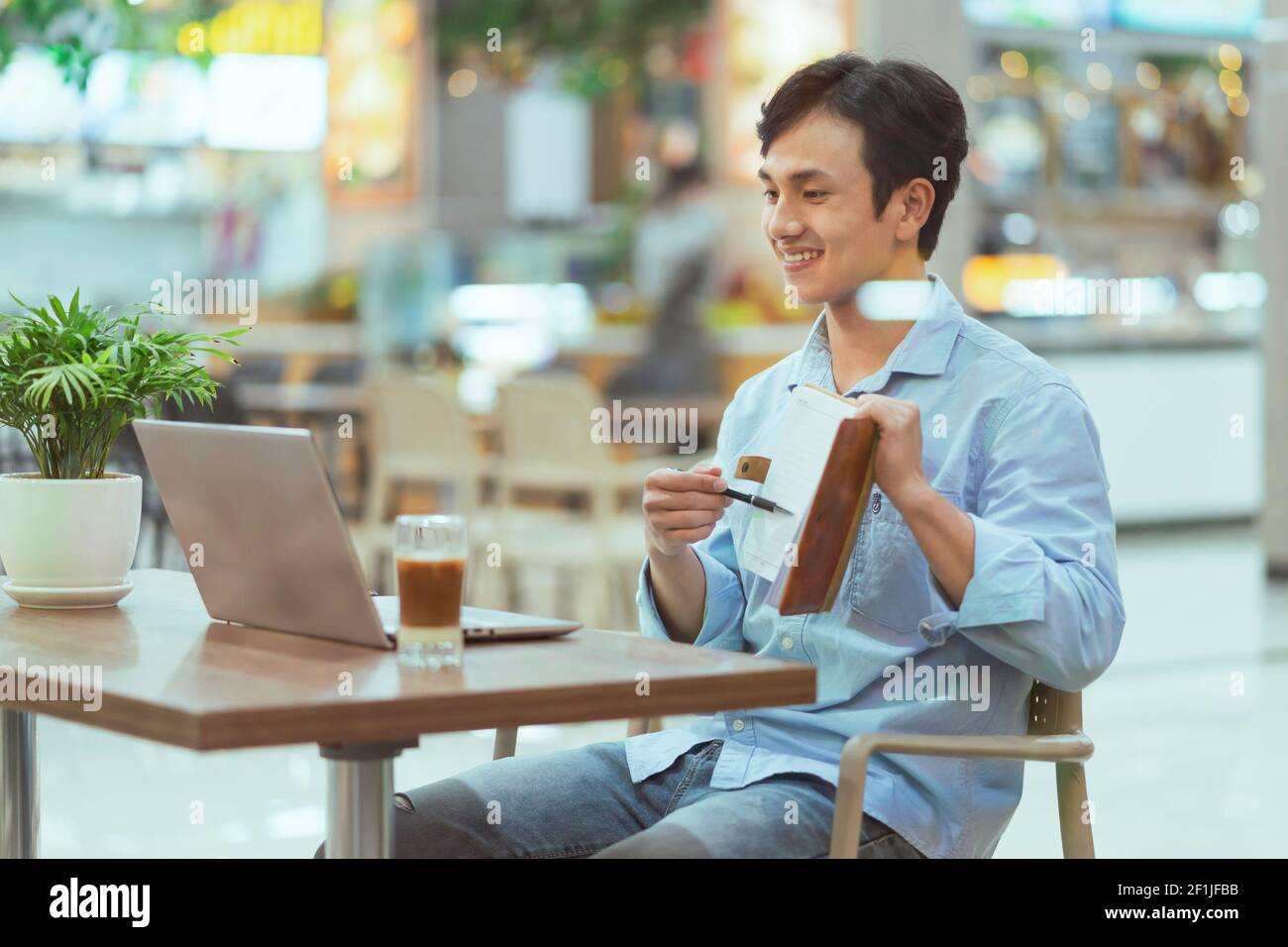 Asian man sitting working alone at a coffee shop Stock Photo - Alamy