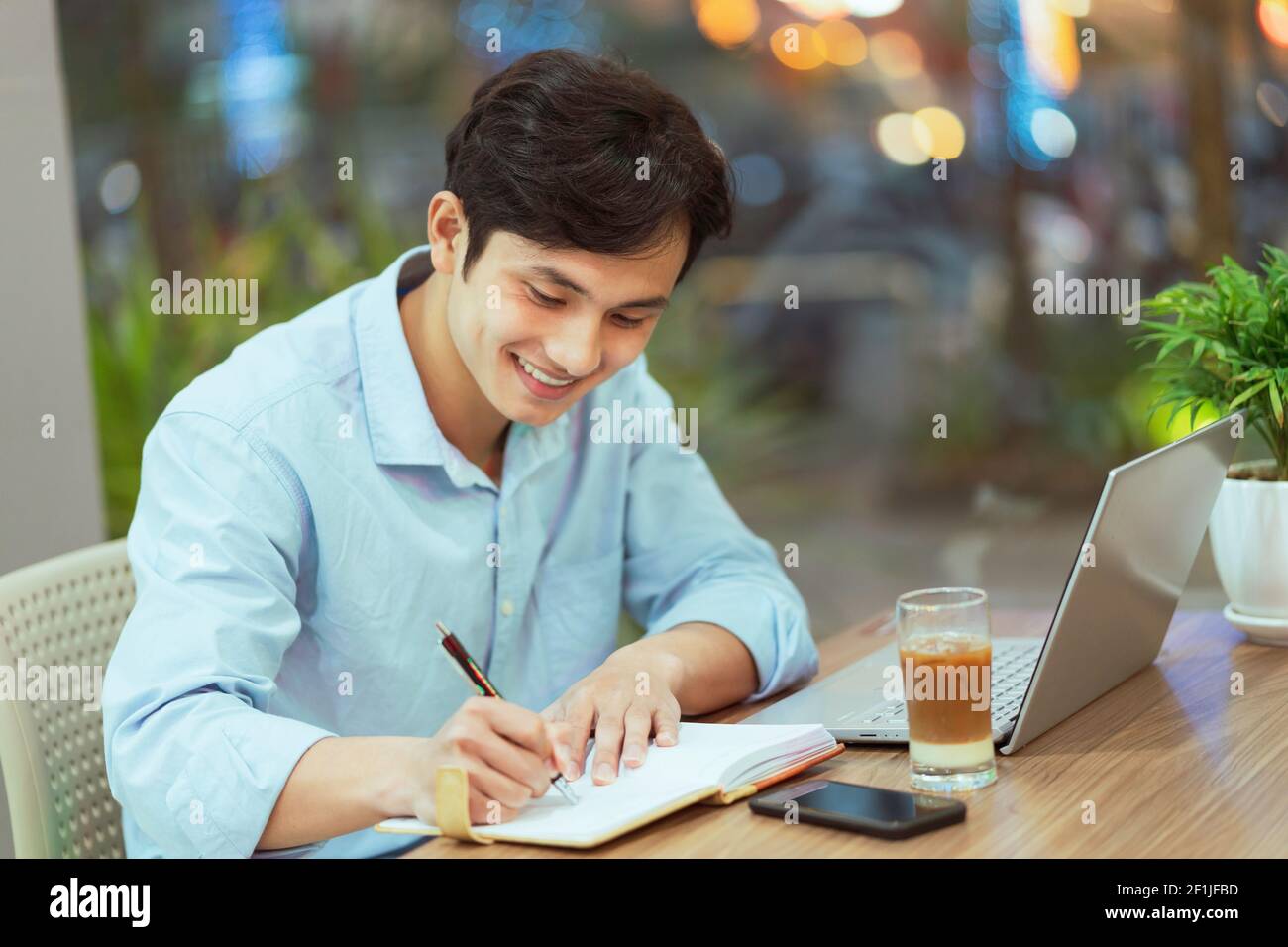 Asian man sitting working alone at a coffee shop Stock Photo - Alamy