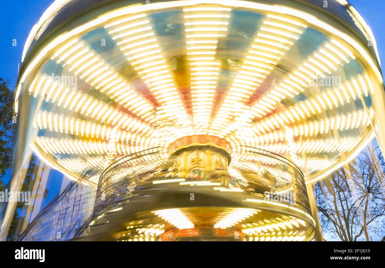 Moving and unfocused effect of a merry-go-round with colorful lights at ...