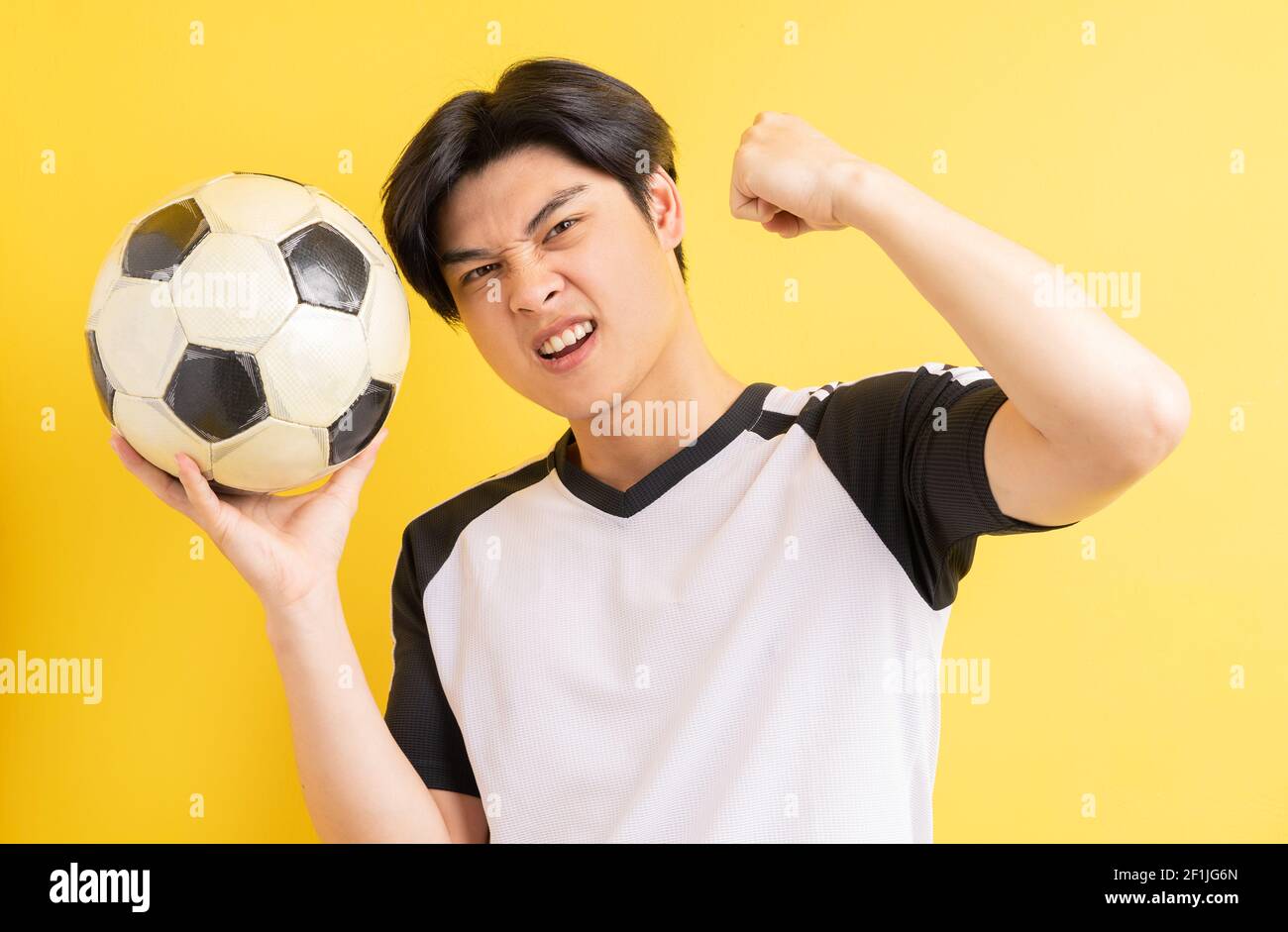 The Asian man is holding the ball and showing a triumphant expression ...