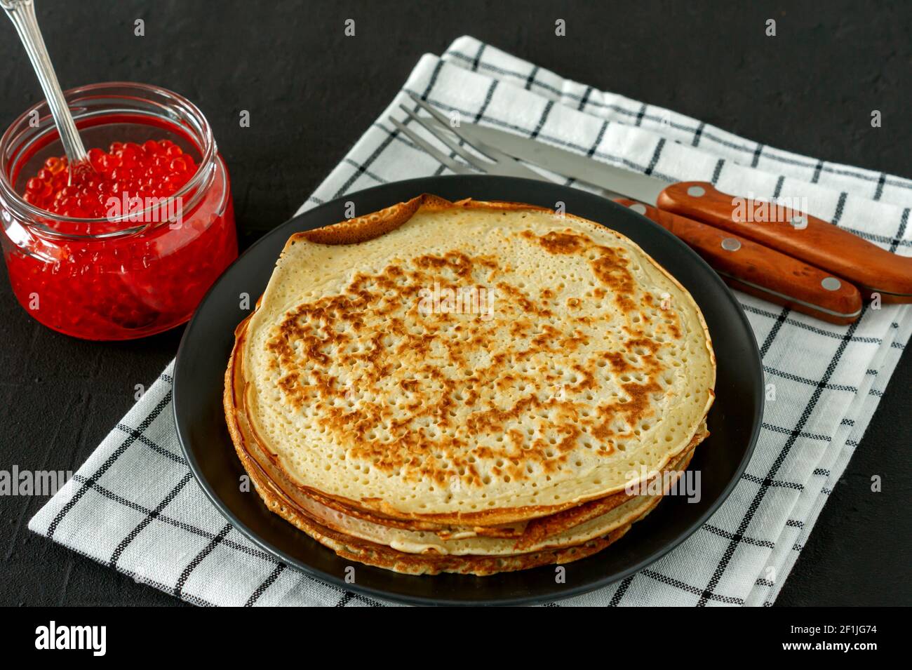 Traditional Russian Crepes Blini stacked in a plate with red caviar on ...
