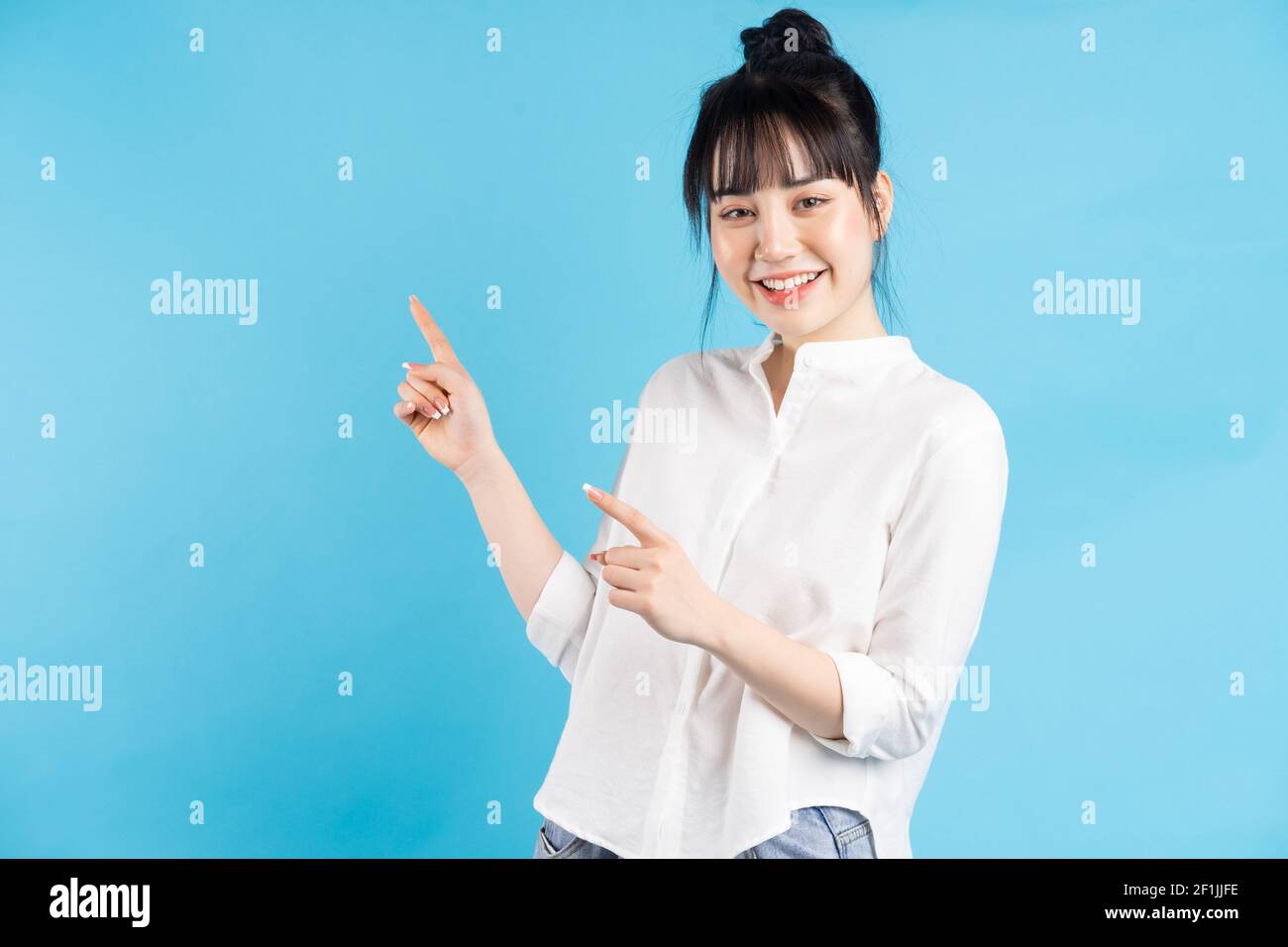 Beautiful Asian woman standing pointing on blue background Stock Photo ...