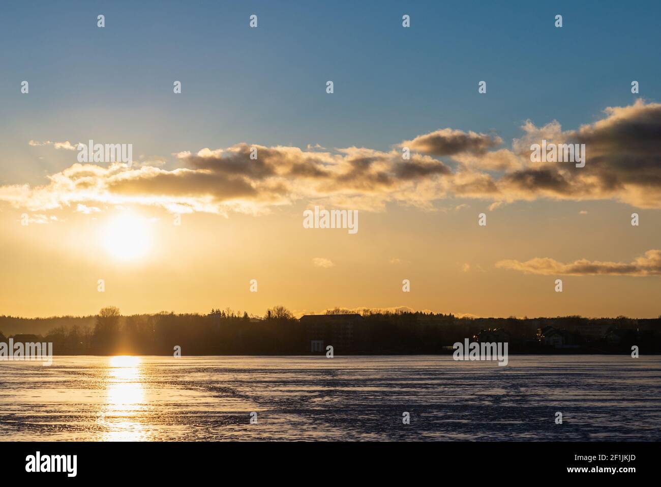 Winter landscape with frozen lake at sunrise or sunset. Lake glistening ...