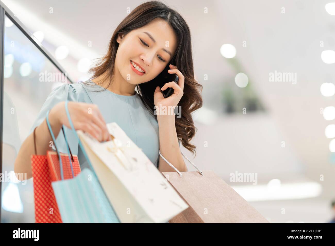 Young girl is shopping and using the phone at the mall Stock Photo - Alamy
